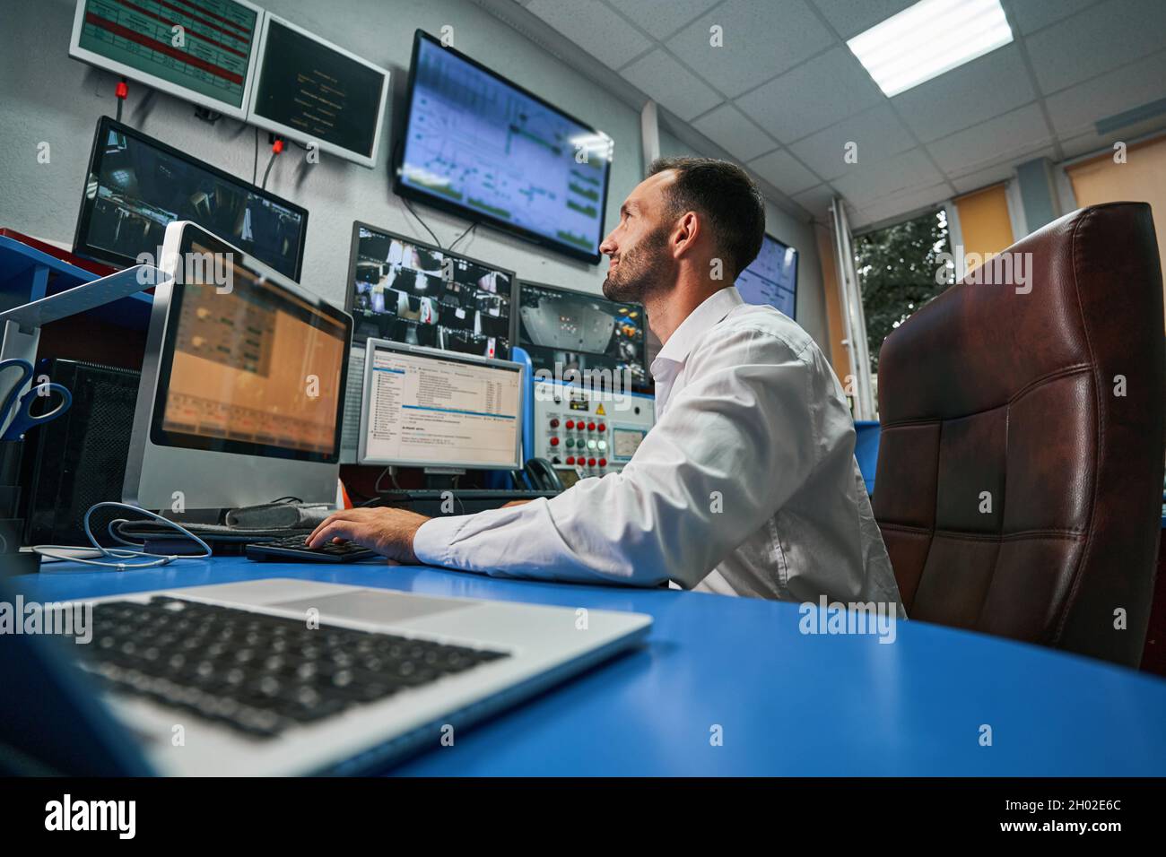 Data center technician at computer watching camera image on screen ...