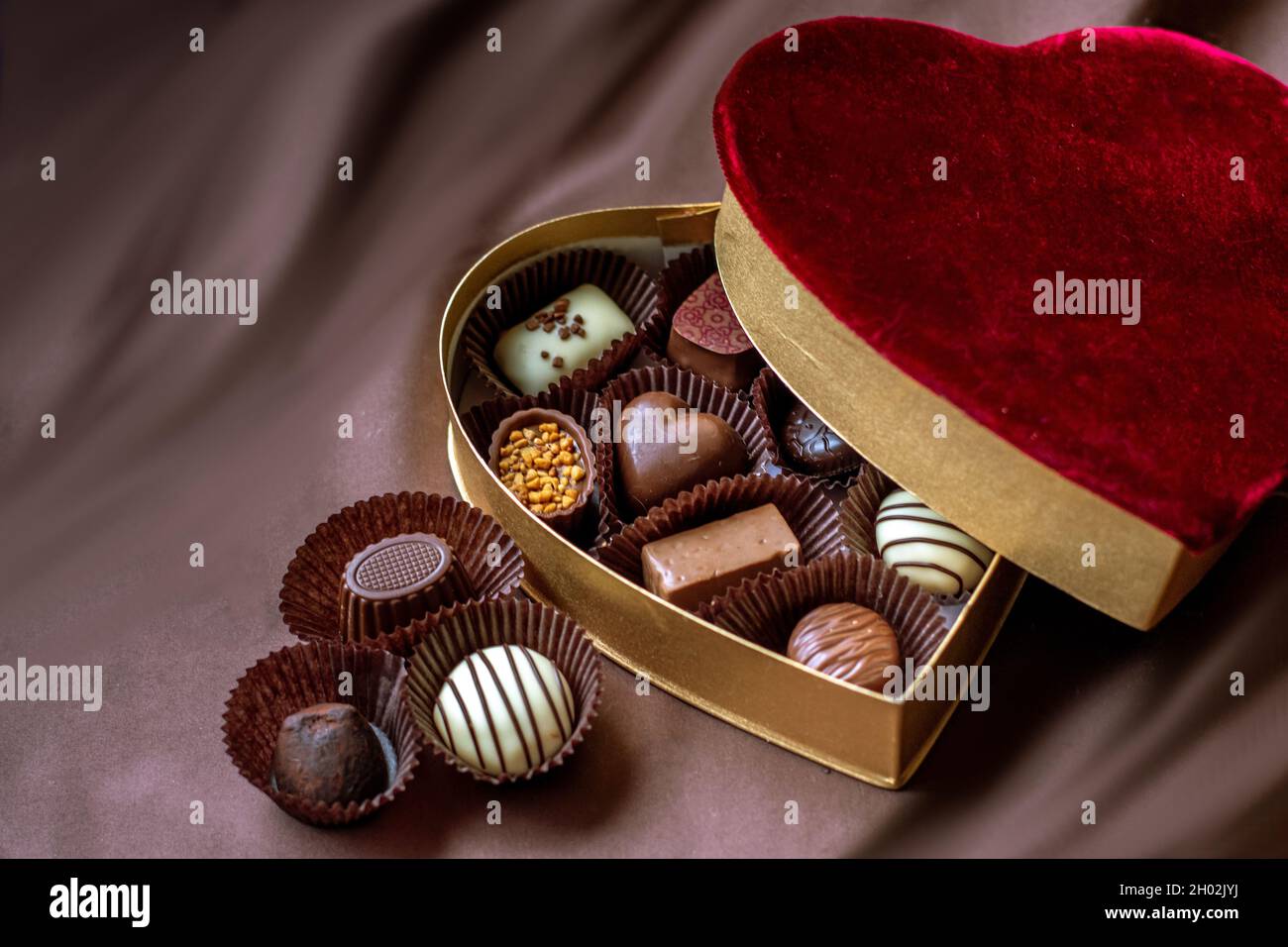 A velvet heart box holds an assortment of delicious gourmet chocolates ...