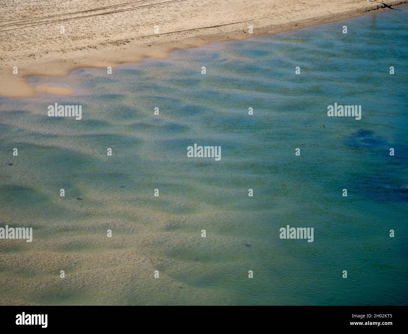 Natural colourful undulating patterns in the beach sand under shallow ...