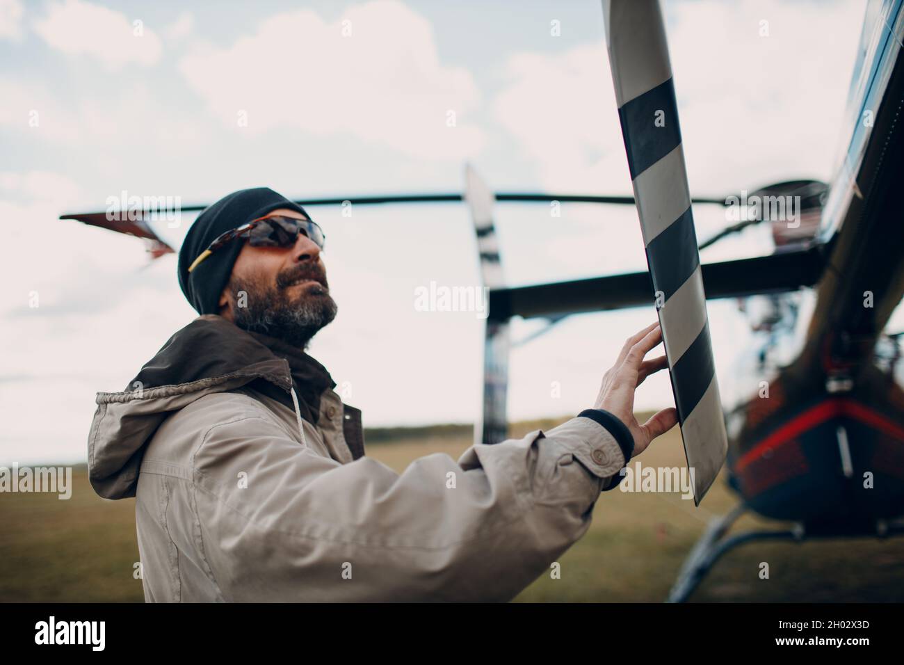 Portrait of helicopter pilot standing near vehicle in field airport ...