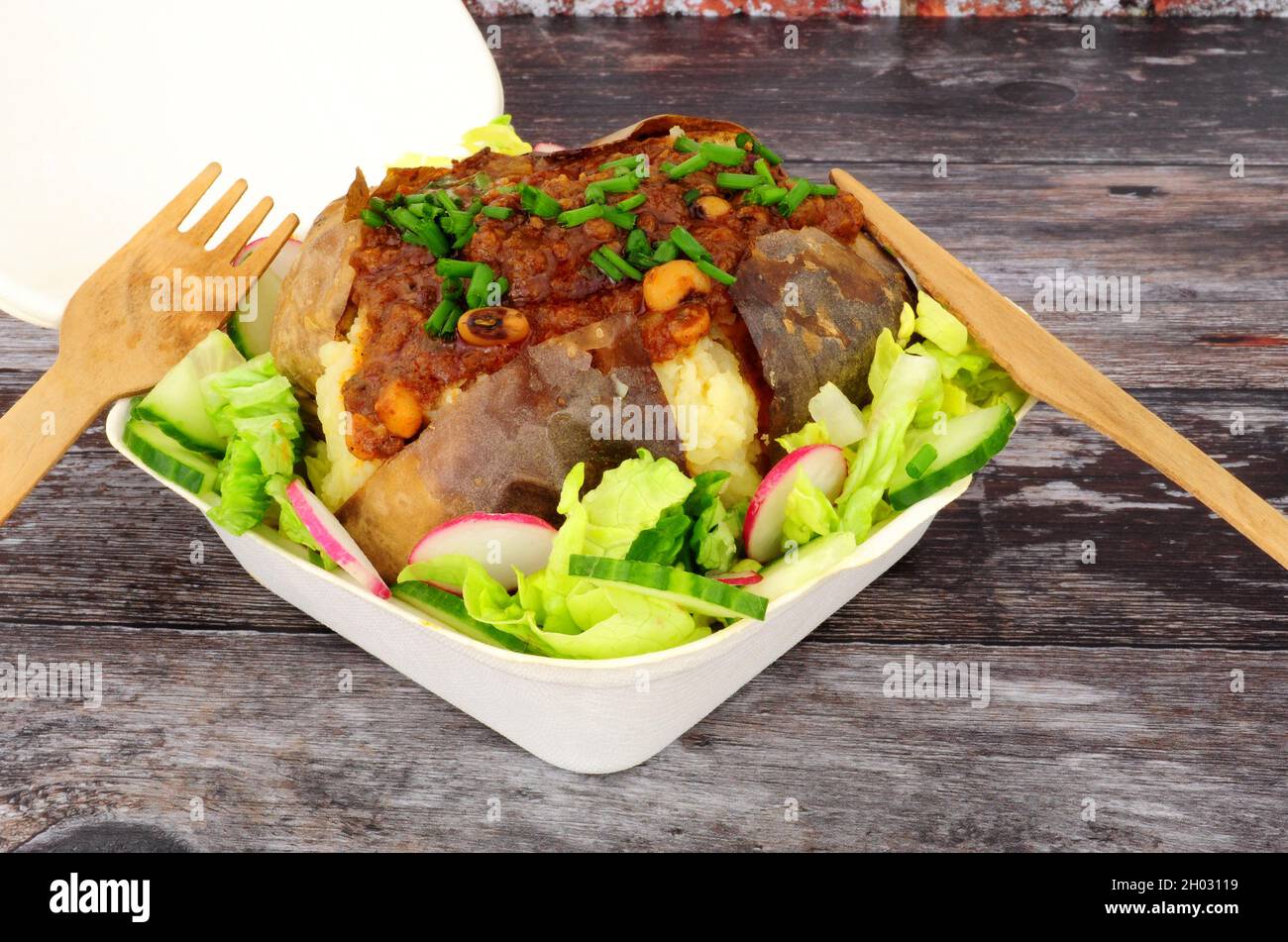 Chilli beef filled baked jacket potato with fresh salad in a take away ...