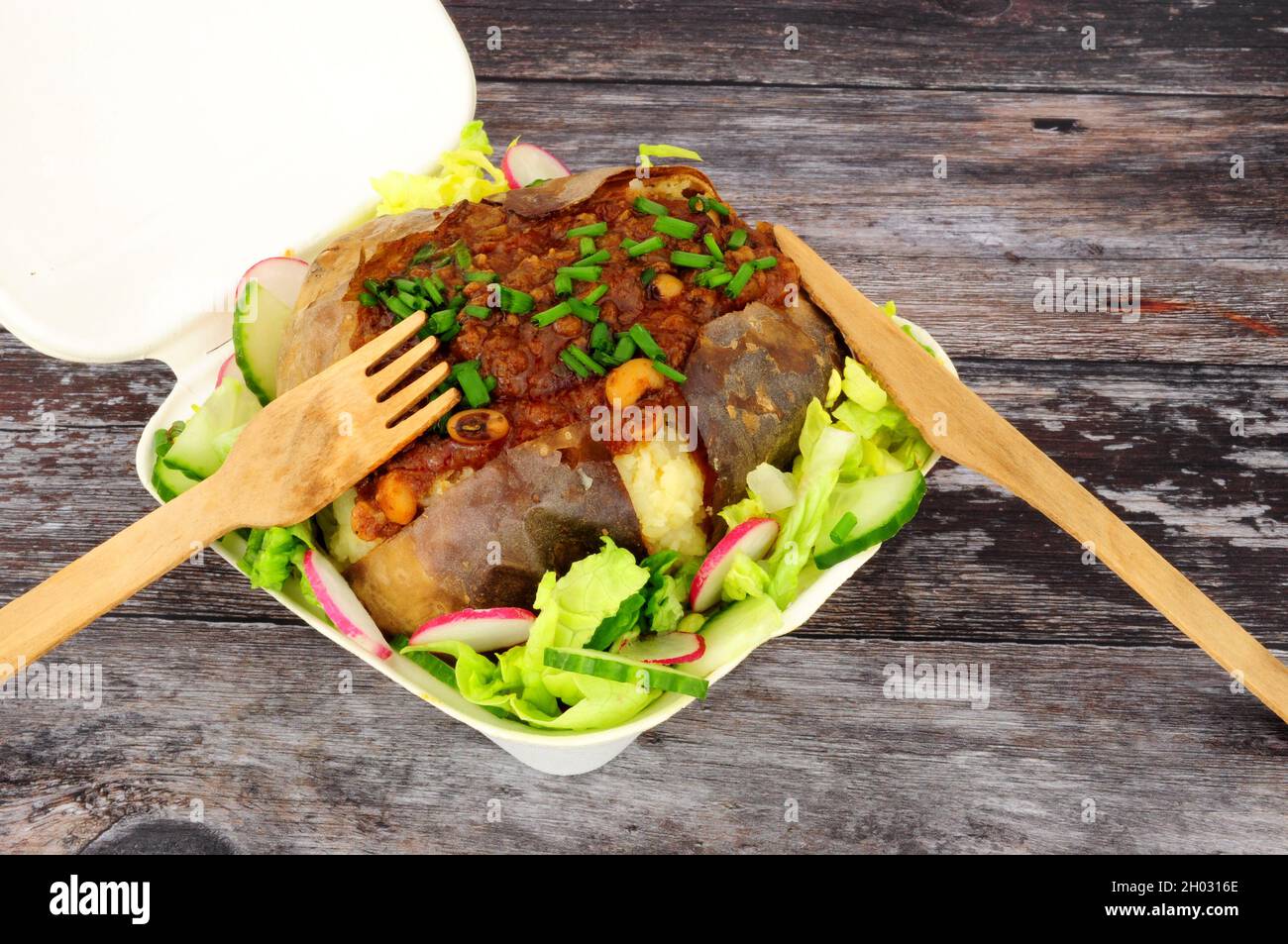Chilli beef filled baked jacket potato with fresh salad in a take away ...