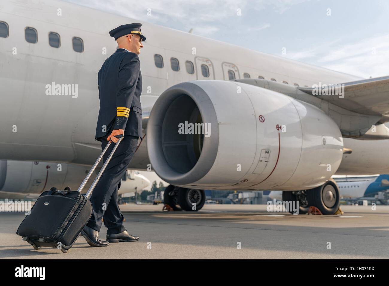 Male pilot walking along commercial airplane outdoors Stock Photo - Alamy
