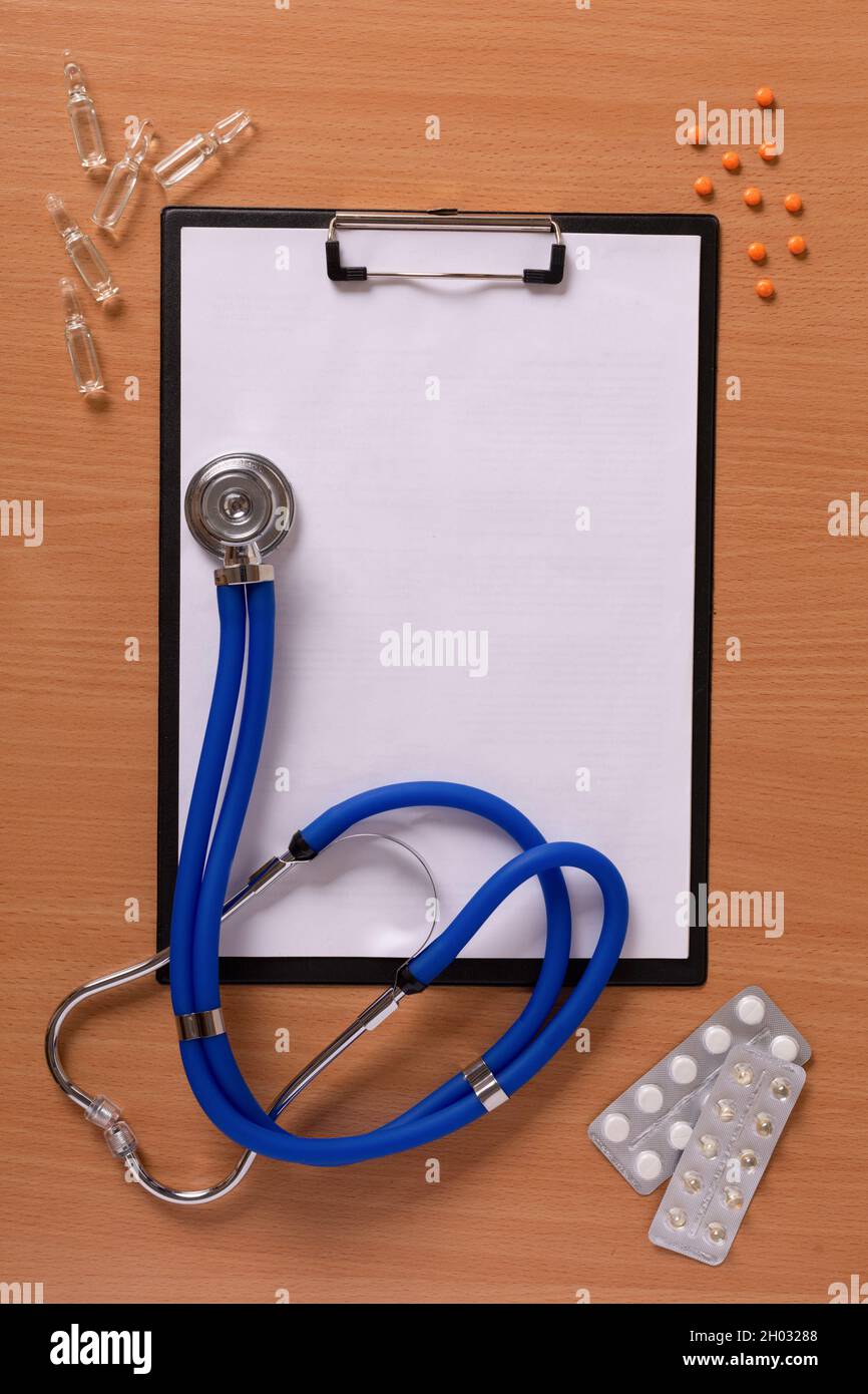 Blank sheet on doctor's tablet, phonendoscope, pills and ampoules ...
