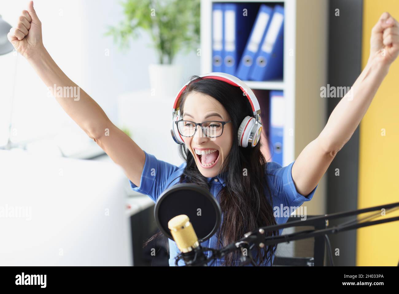 Joyful enthusiastic presenter in headphones with microphone looks at ...