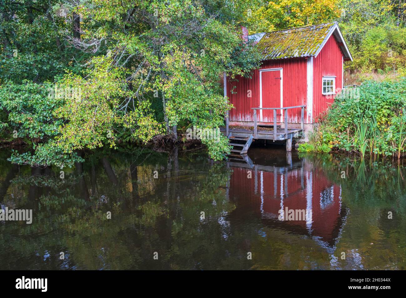 Small red cottage by the water with a bathing jetty Stock Photo - Alamy