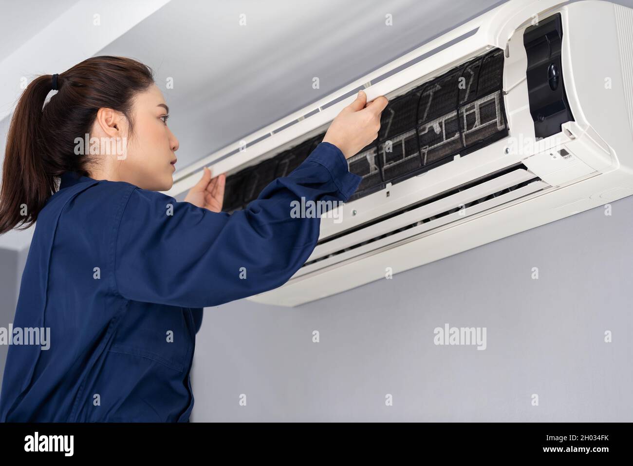female technician service open the air conditioner indoor for checking ...