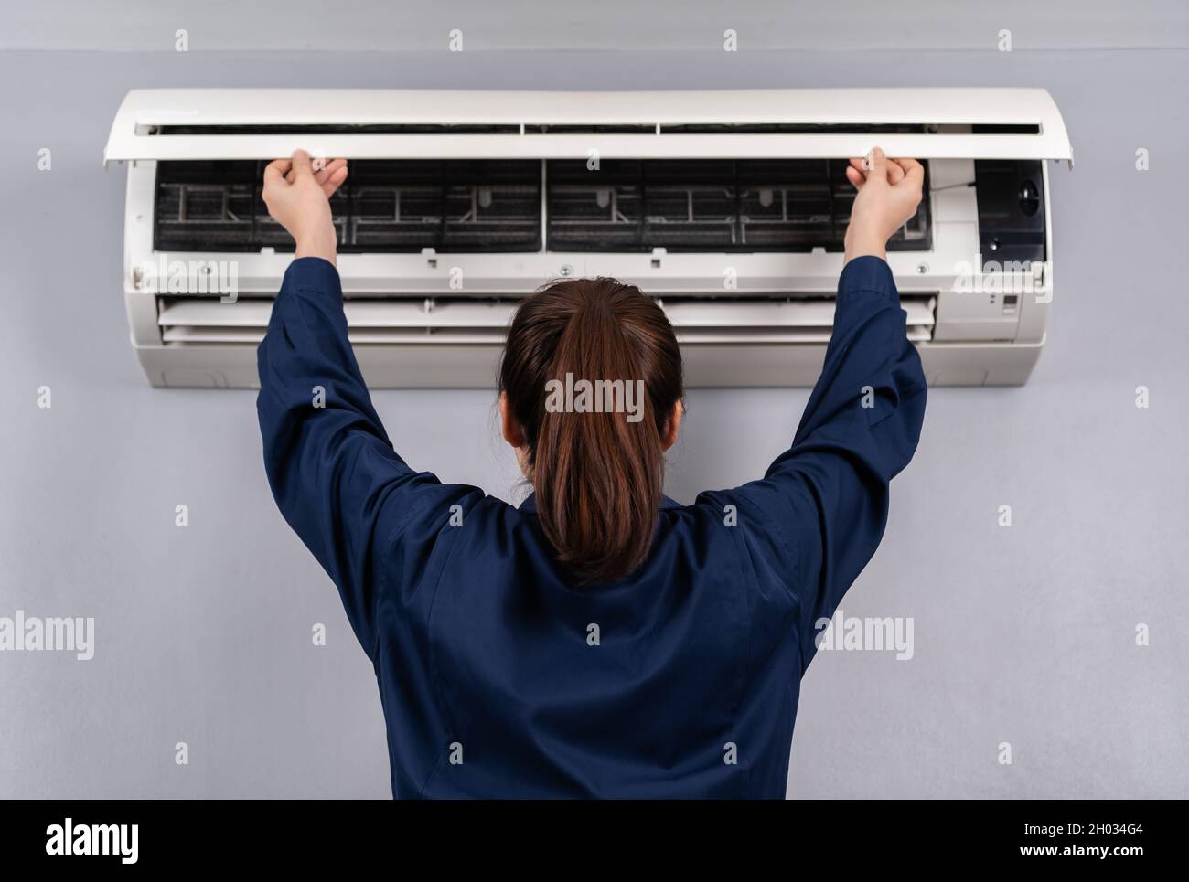 female technician service open the air conditioner indoor for checking ...