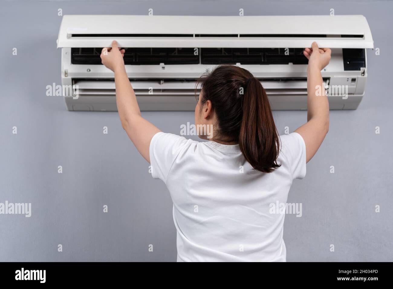 young woman open the air conditioner indoor at home Stock Photo - Alamy