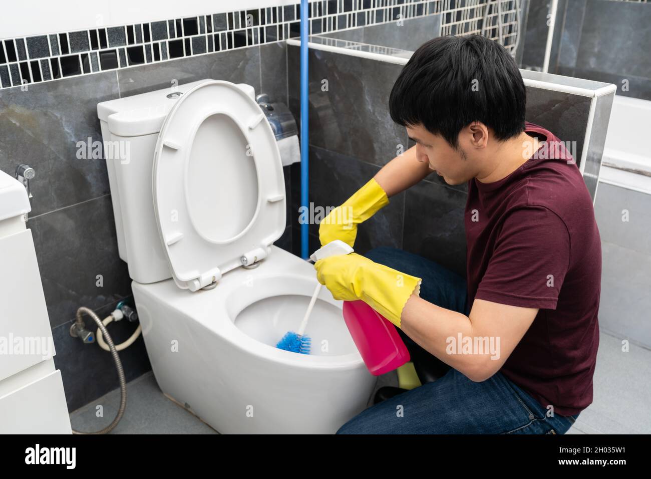 young man cleaning toilet bowl in bathroom Stock Photo - Alamy