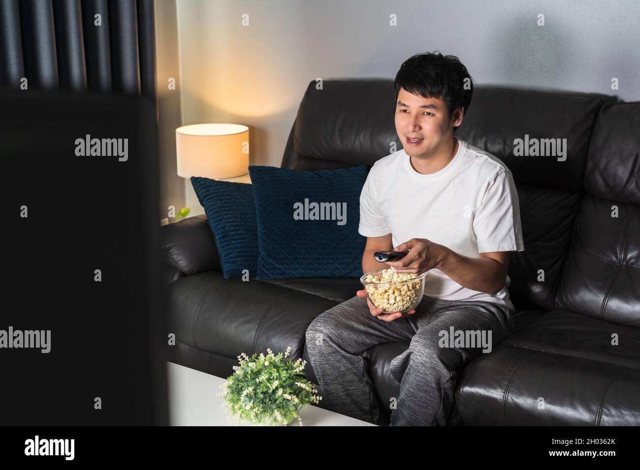 happy young man watching TV on sofa at night Stock Photo - Alamy