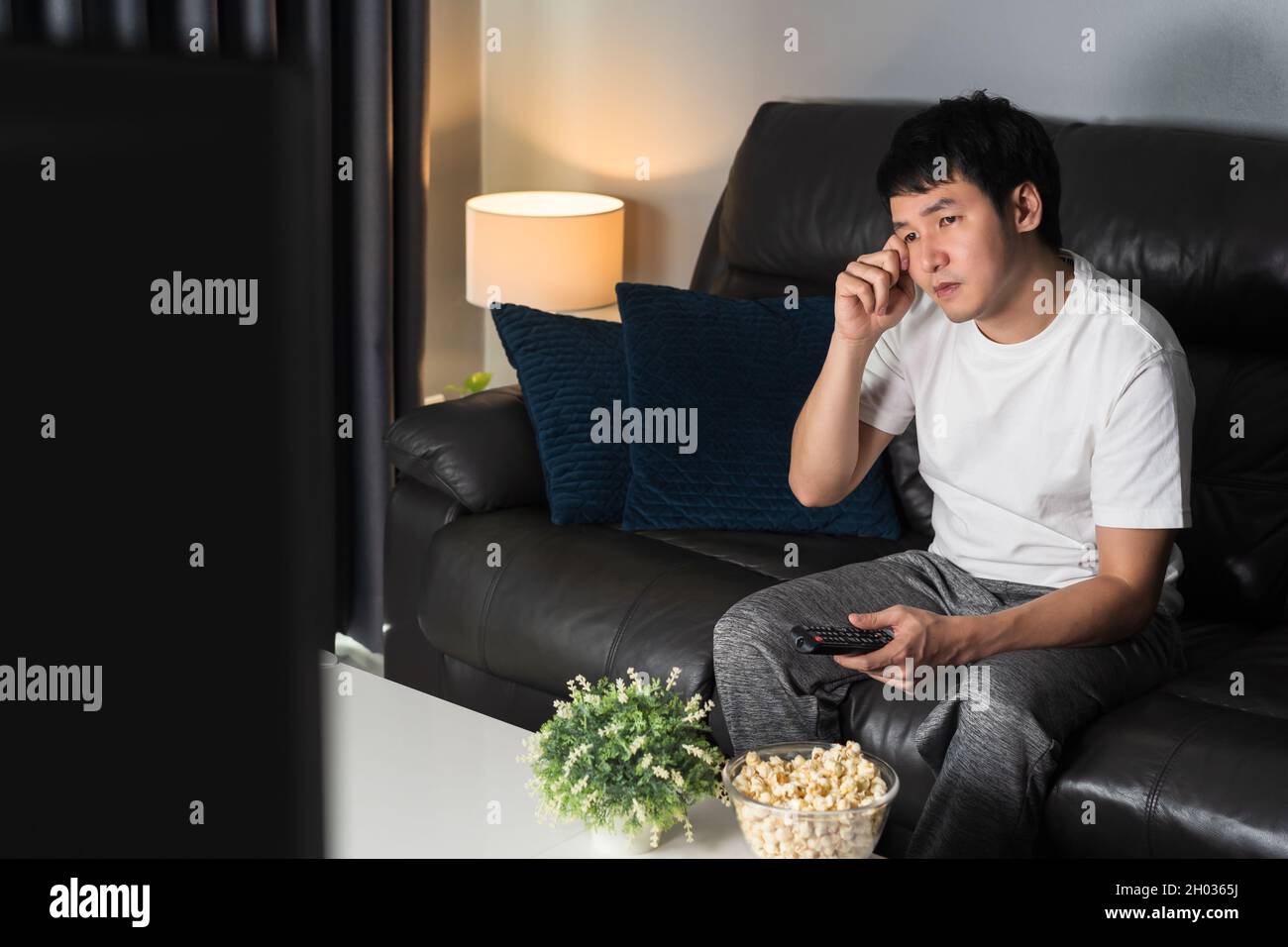 sad young man watching television and crying on sofa at night Stock ...