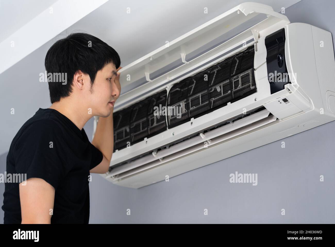 young man open the air conditioner indoor at home Stock Photo - Alamy