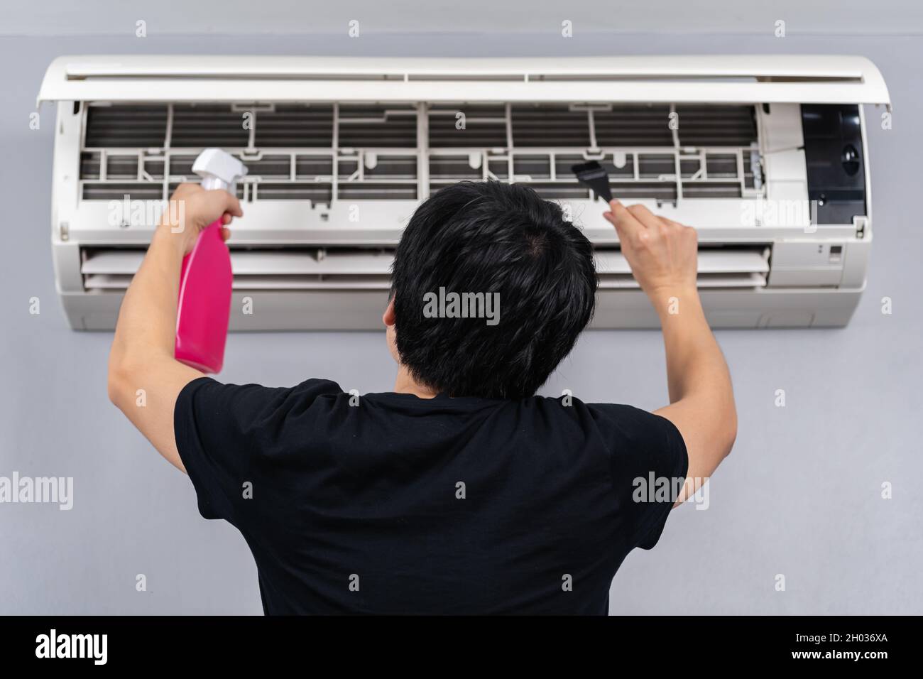 young man cleaning the air conditioner indoors at home Stock Photo - Alamy