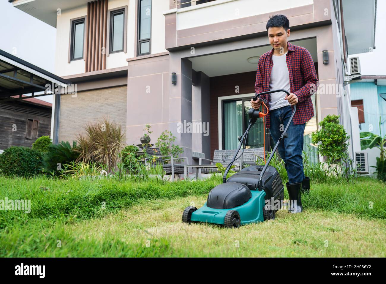 man using a lawn mower cutting grass at home Stock Photo - Alamy