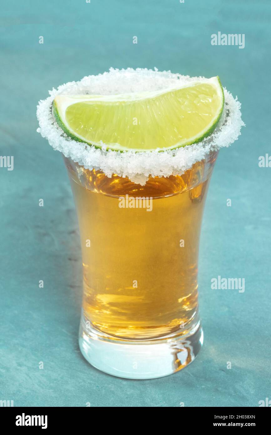 Gold tequila shot, with a salt rim and a lime slice, an angle close-up ...