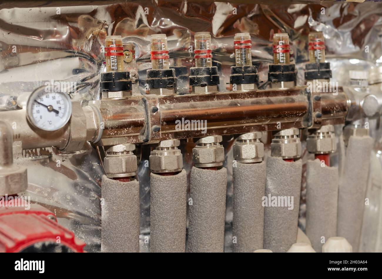 Floor heating manifold installed on the wall. Insulated water supply ...