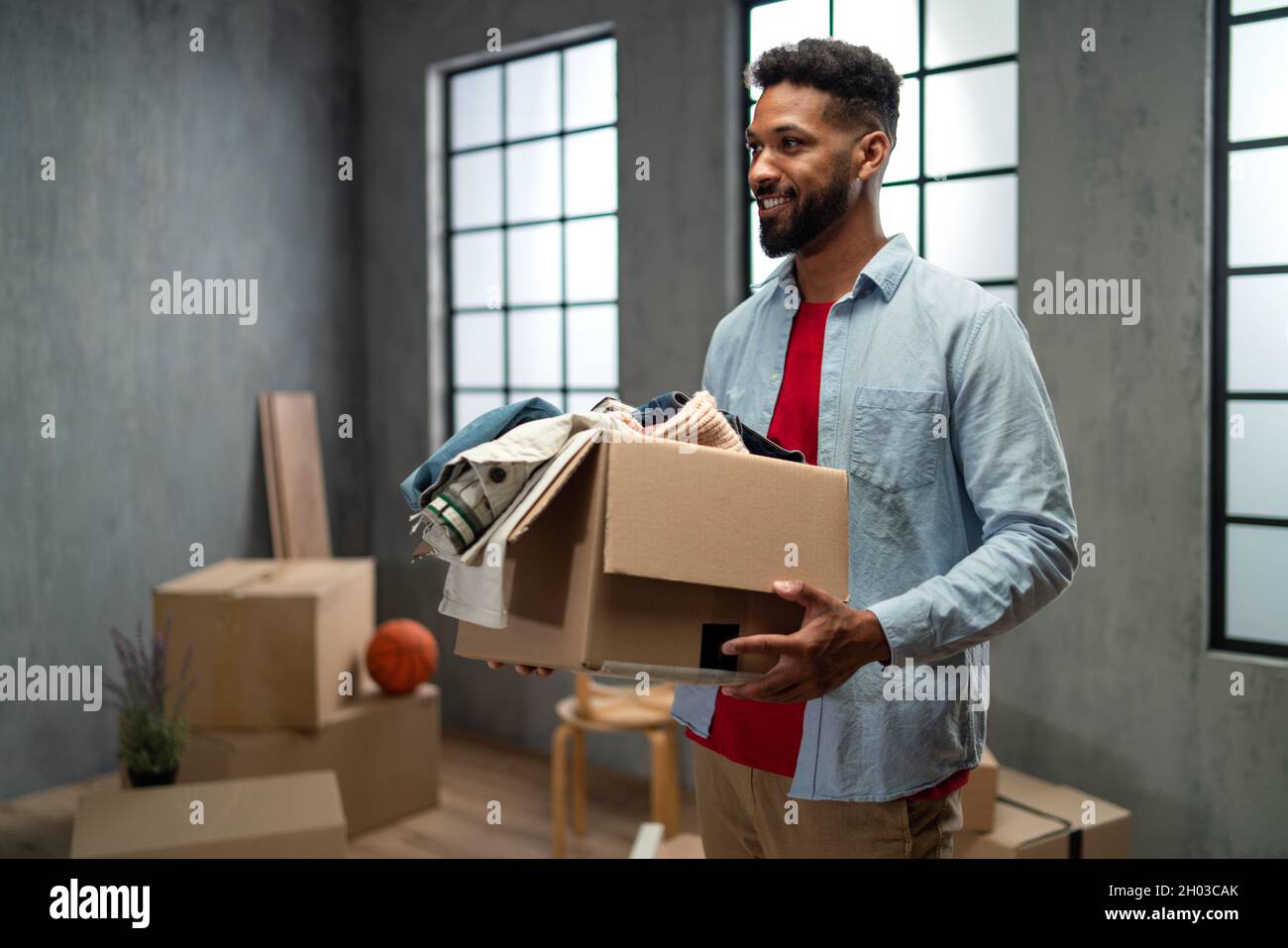 Happy young man holding packing boxes moving home, new living concept ...