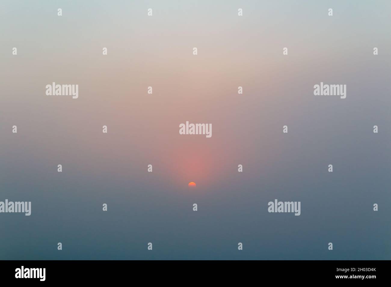 Detail of sun rise through heavy fog with blue sky Stock Photo - Alamy