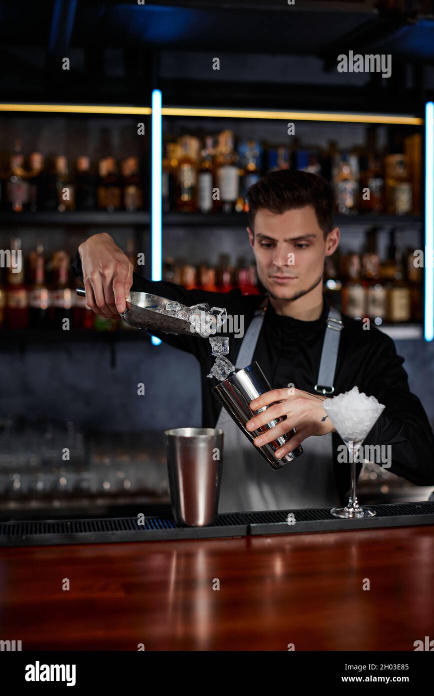 Barman puts the ice cubes into a glass Stock Photo - Alamy
