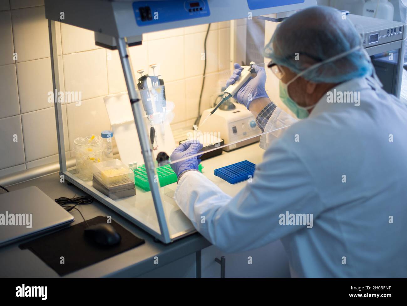 Biologist with protective equipment working on samples in insulation ...