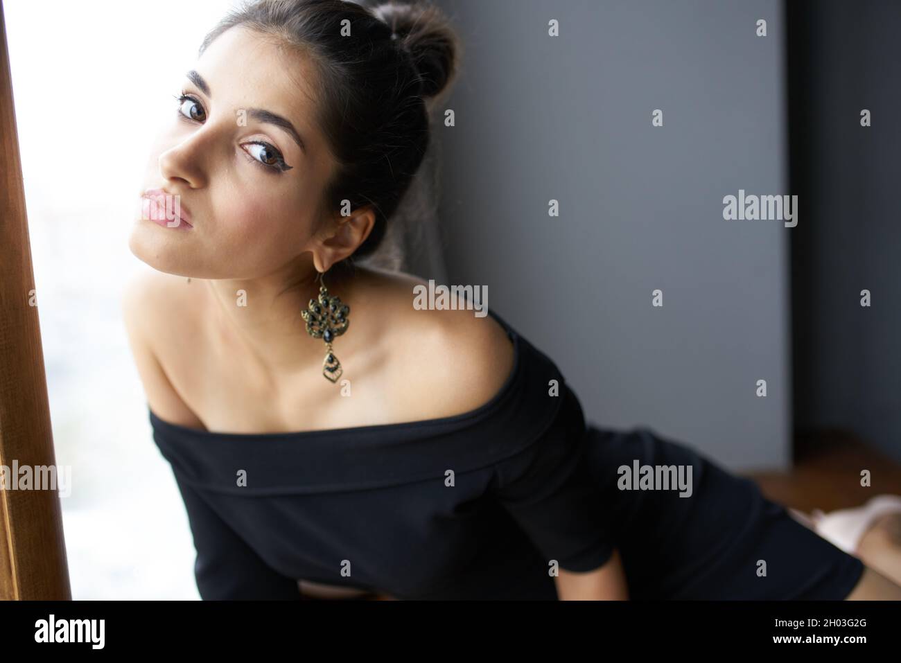 beautiful woman in a black dress near the window posing elegant style ...