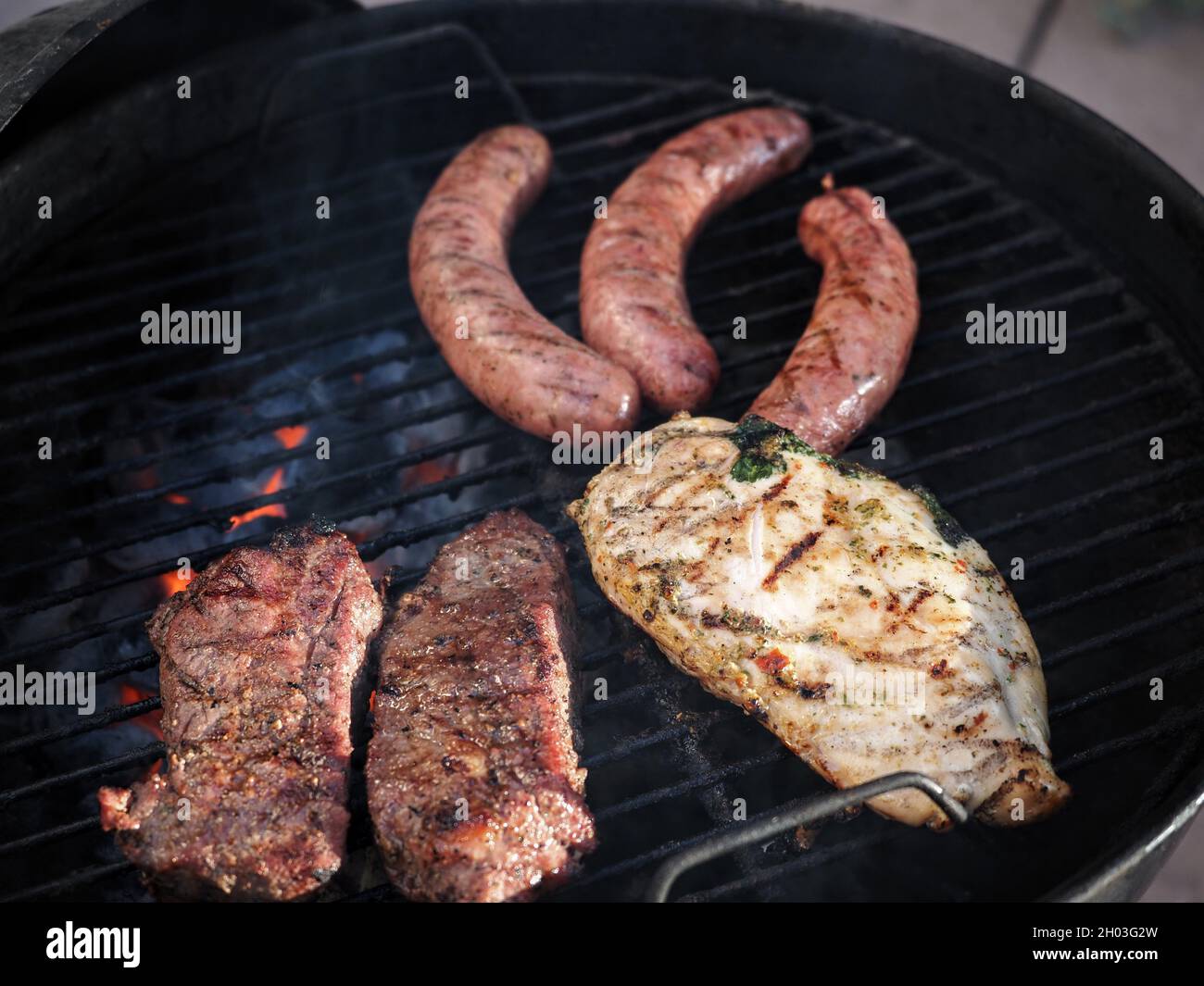 Closeup shot of sausages and pork ribs being grilled on a barbeque with ...