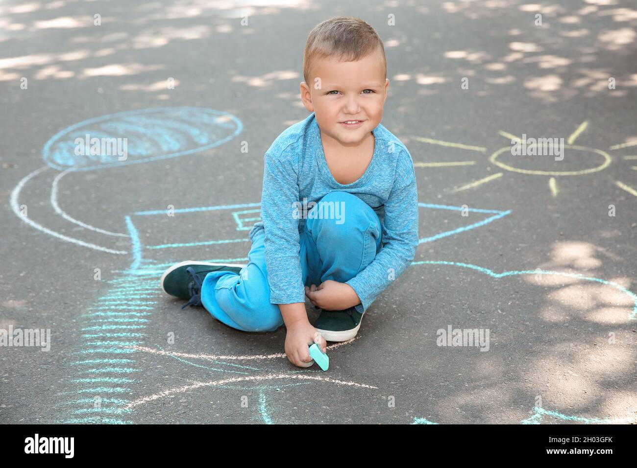 Little child drawing with colorful chalk on asphalt Stock Photo - Alamy
