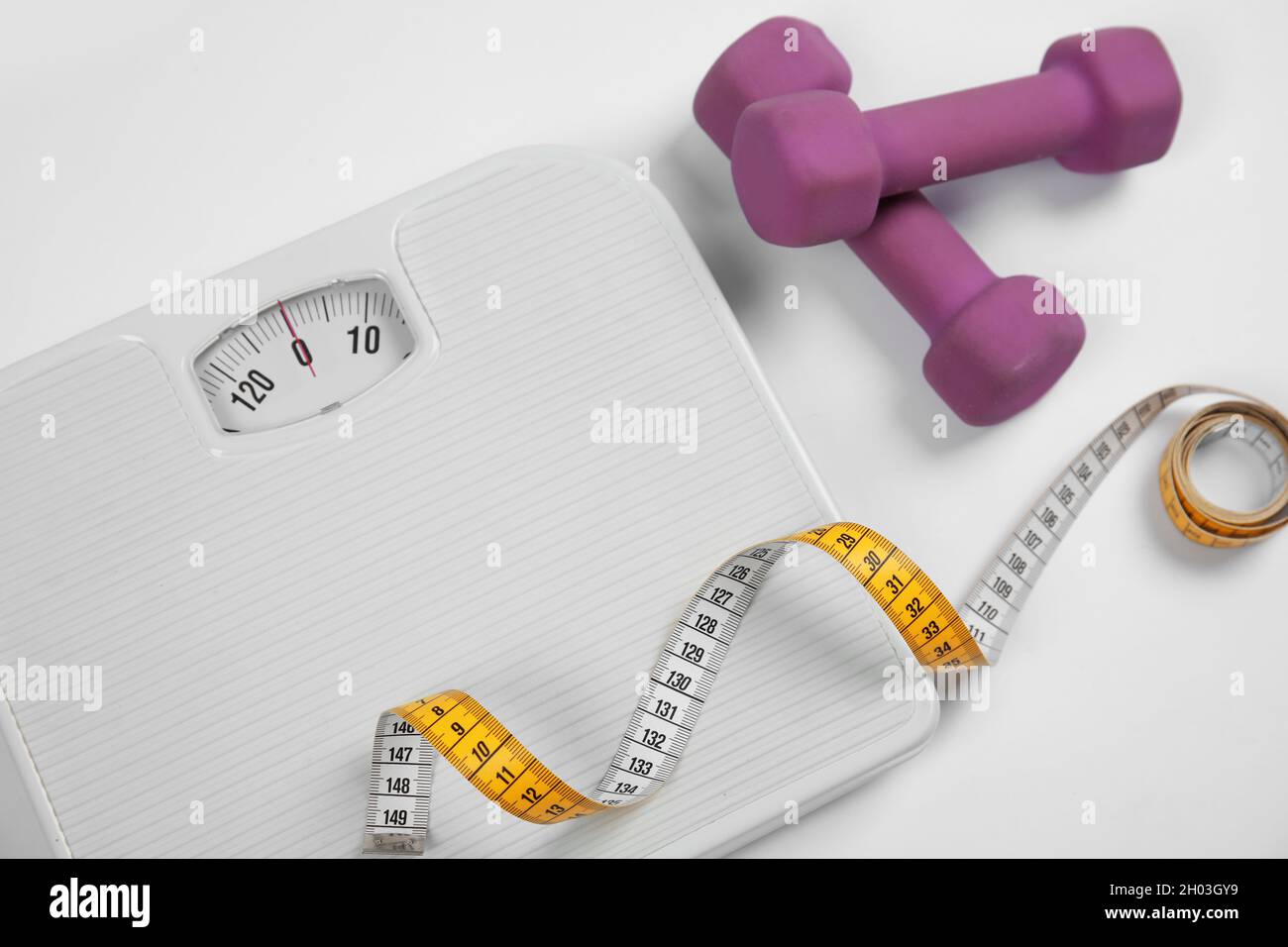 Modern scales, tape measure and dumbbells on white background Stock ...