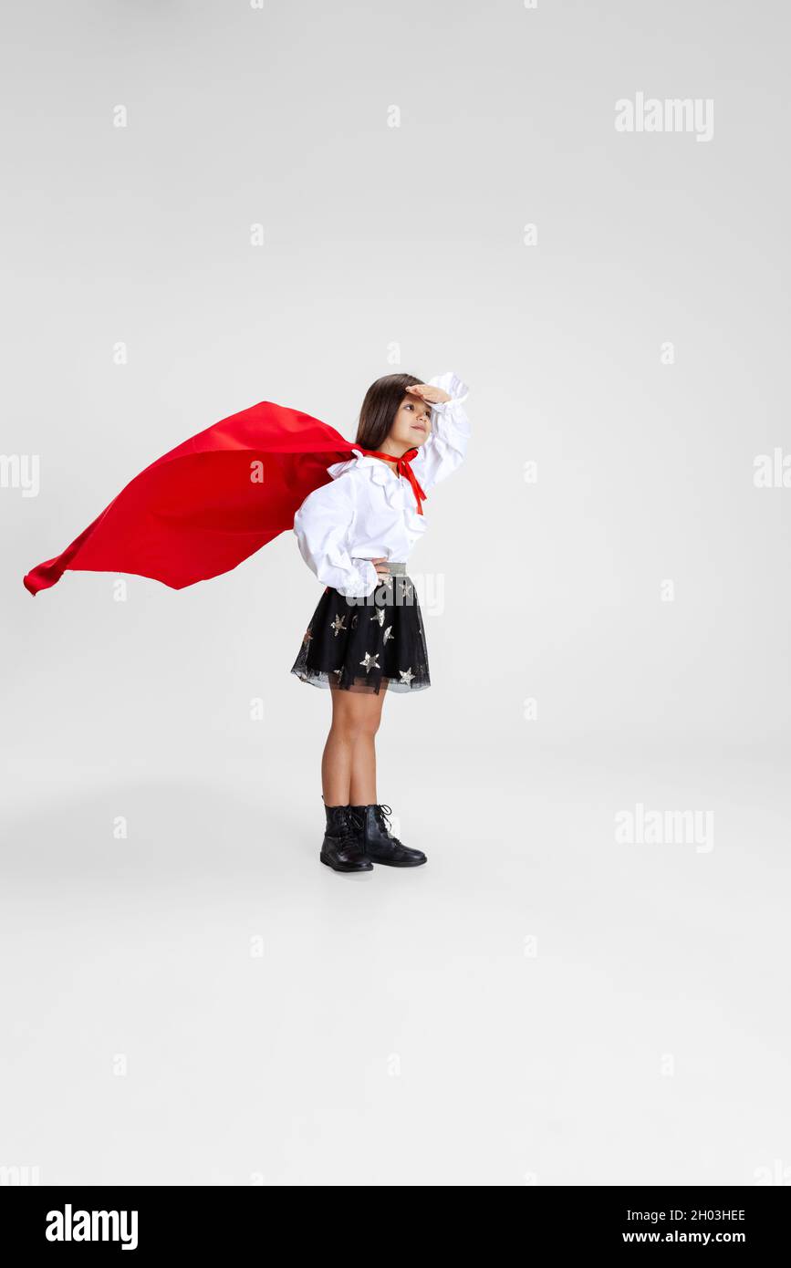 Portrait of beautiful caucasian little girl wearing red cape standing ...