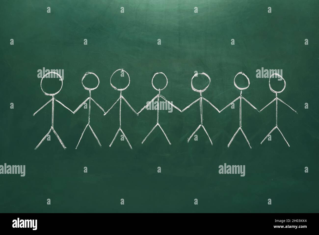 Drawing of people holding hands together on chalkboard. Unity concept ...