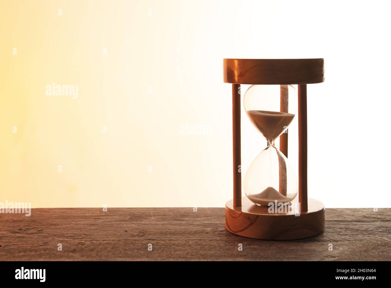 Hourglass with flowing sand on table against light background. Time ...