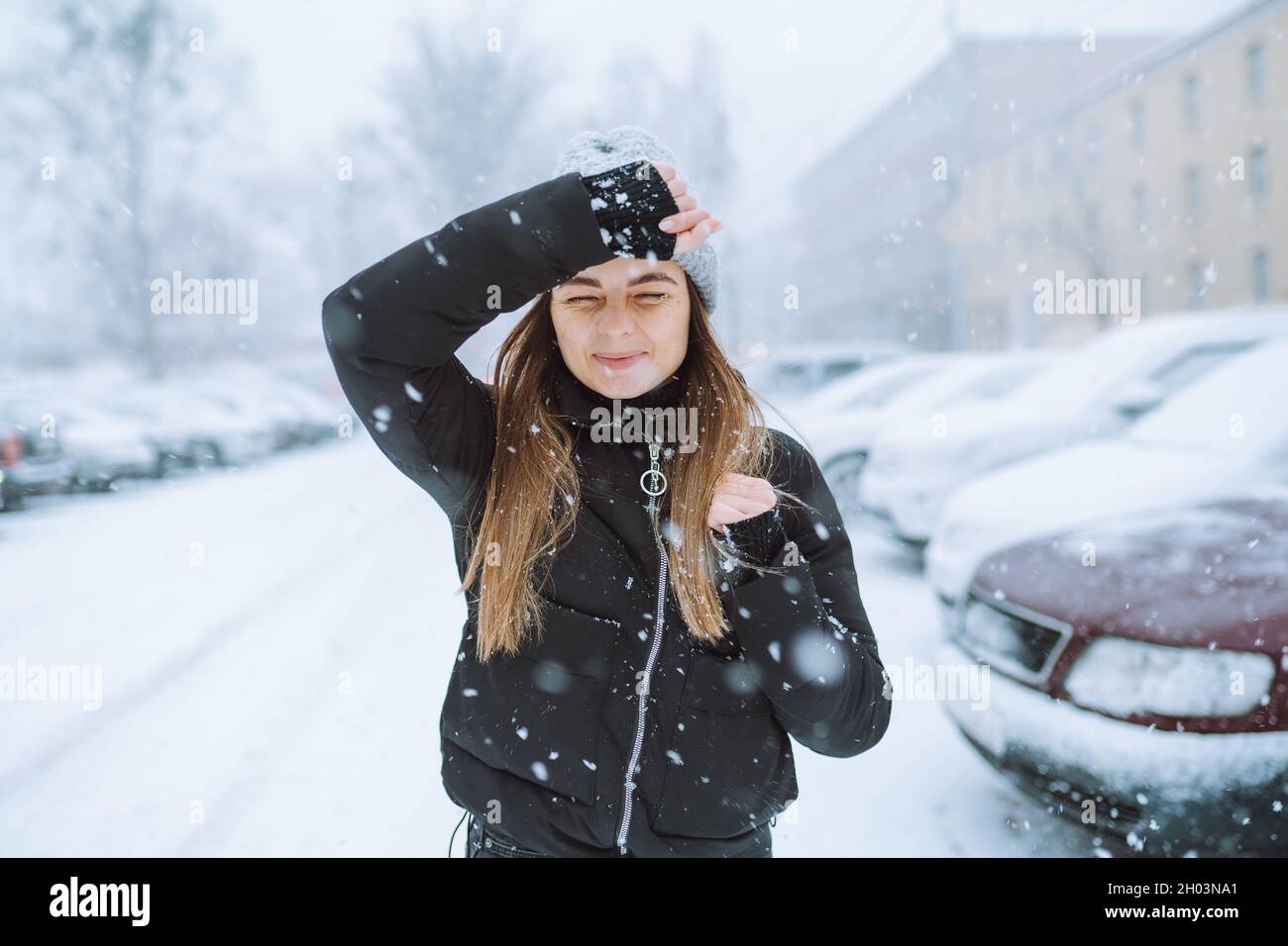 Outdoor portrait of young woman on street under snowfall. Bad cold ...