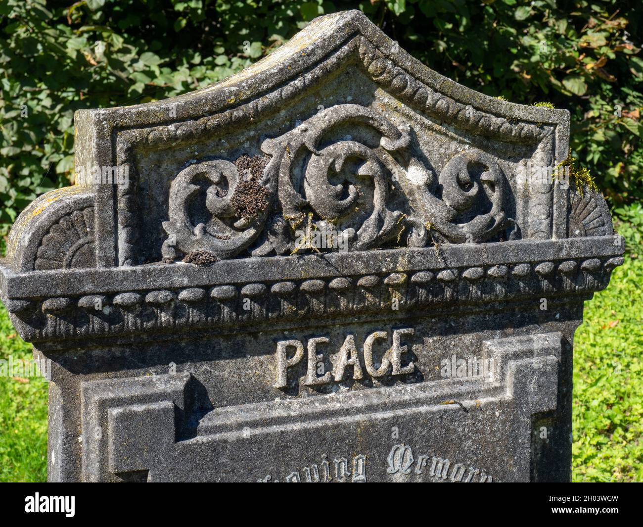 Old carved headstone, inscribed with the word peace, in the churchyard ...