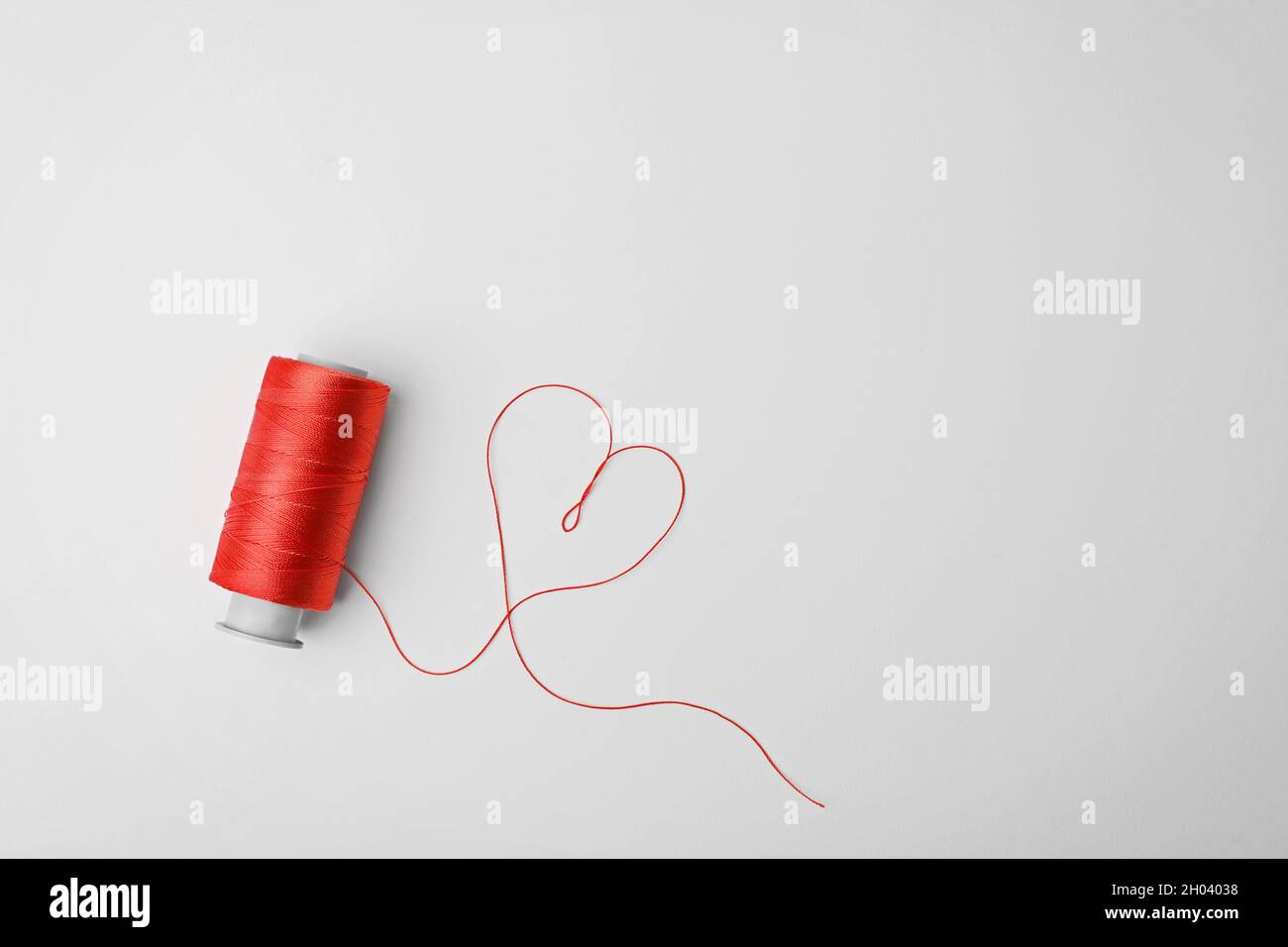 Heart made of color sewing thread and spool on white background, top ...
