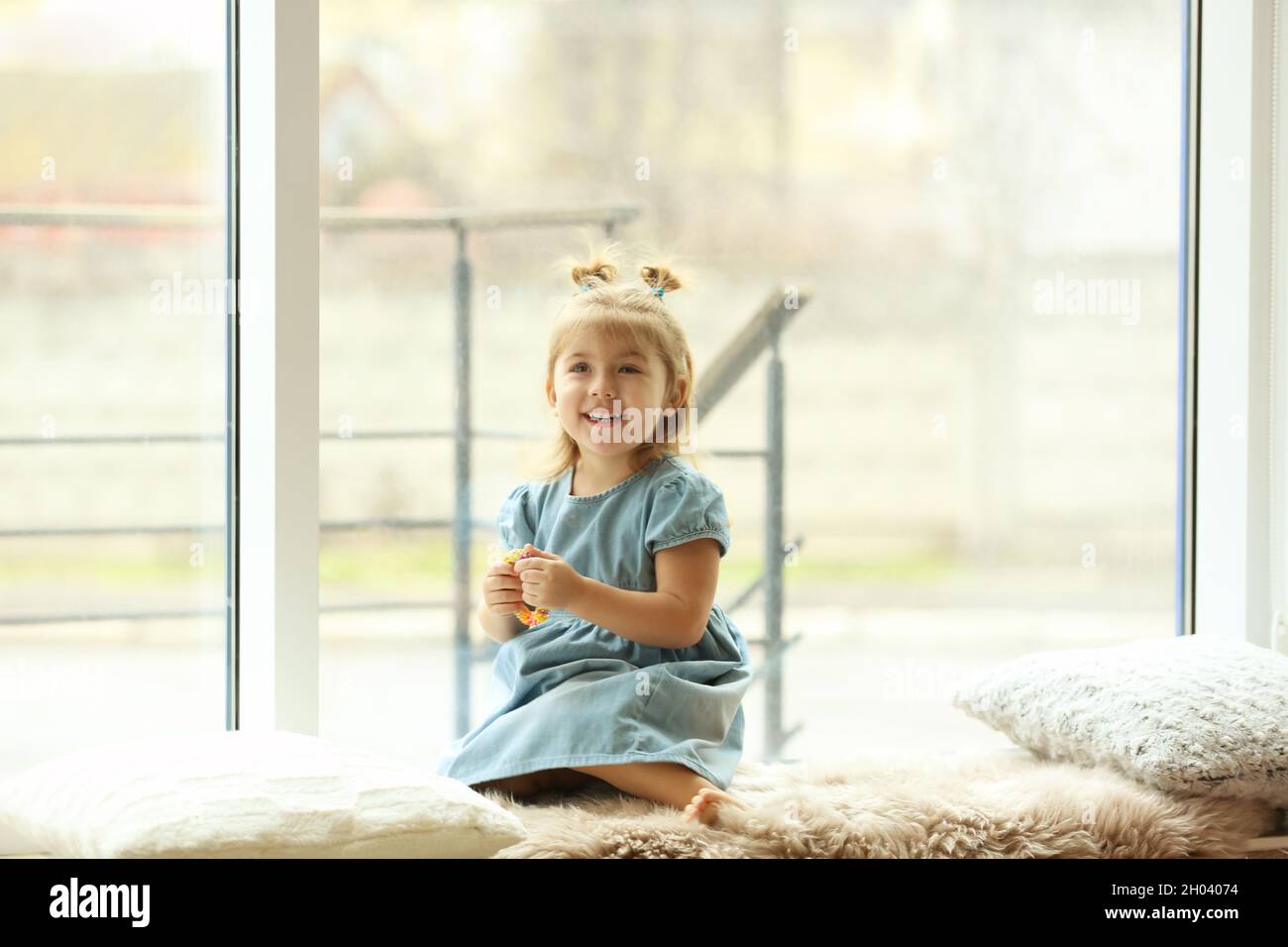 Cute little girl near window at home Stock Photo - Alamy