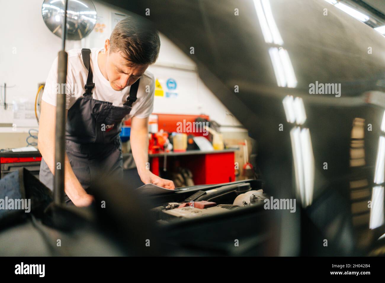 Portrait of focused handsome professional male car mechanic in blue ...