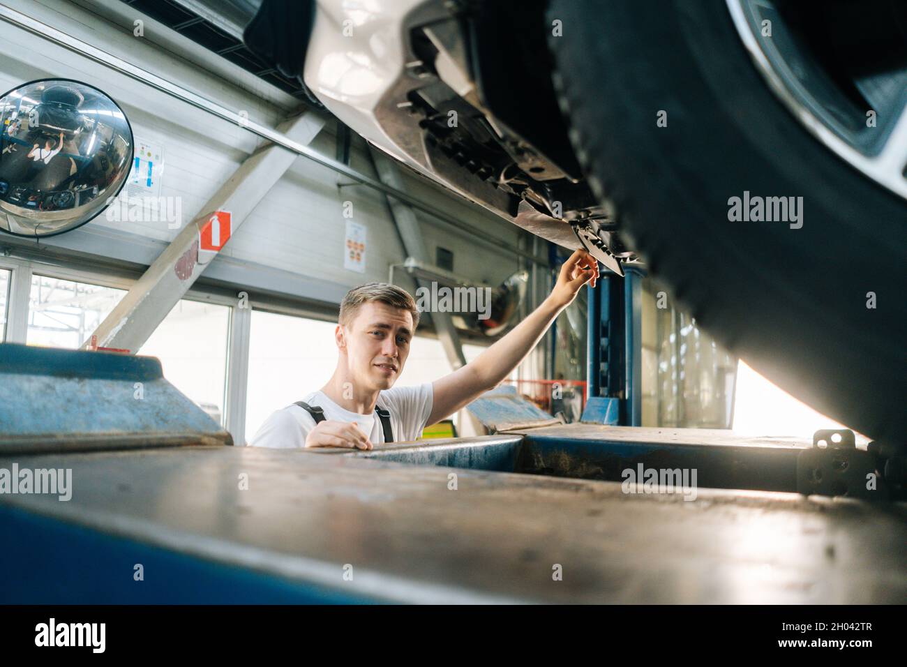 Handsome professional male car mechanic wearing uniform standing in car ...
