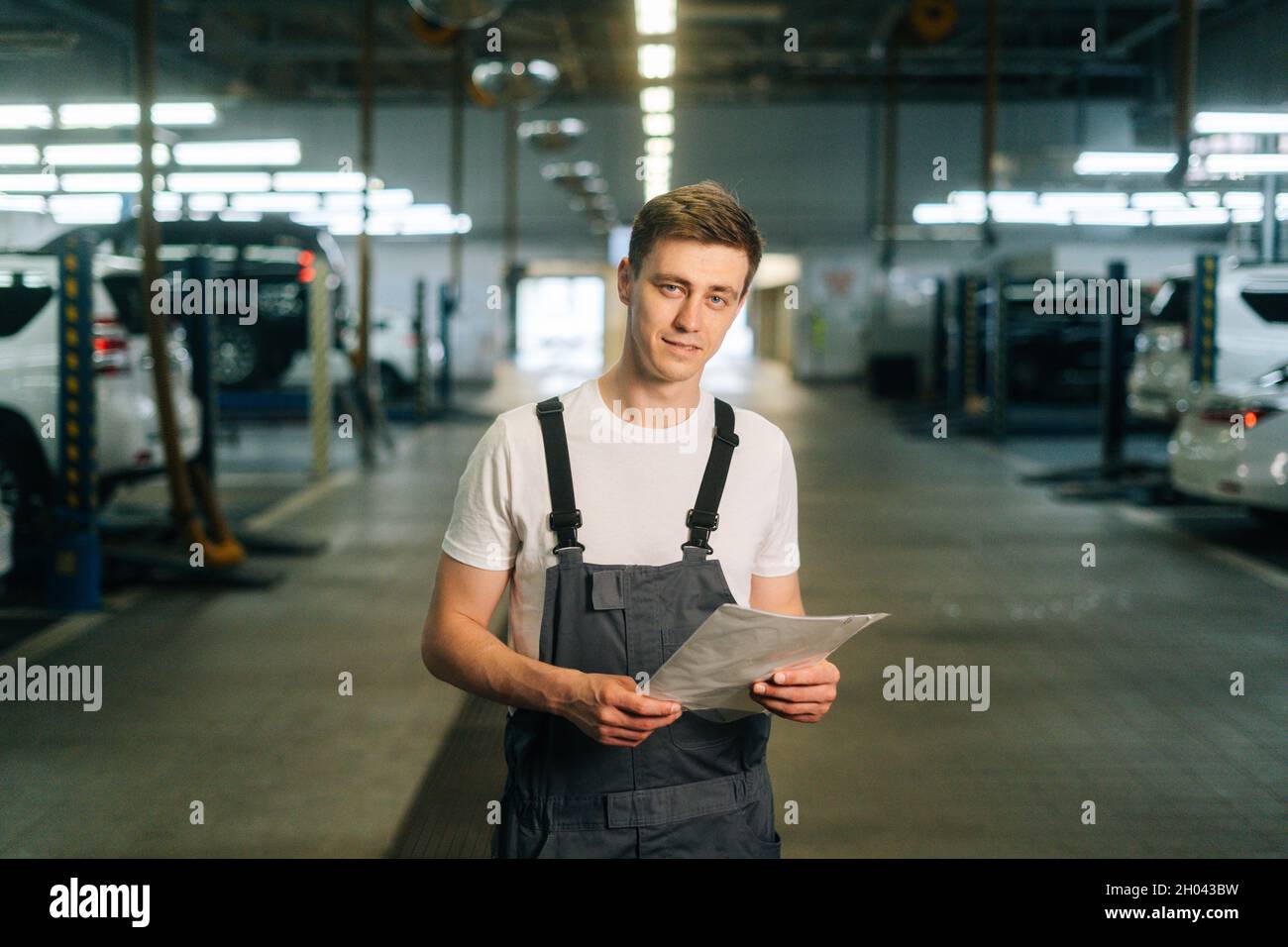 Medium shot portrait of smiling handsome young mechanic male wearing ...