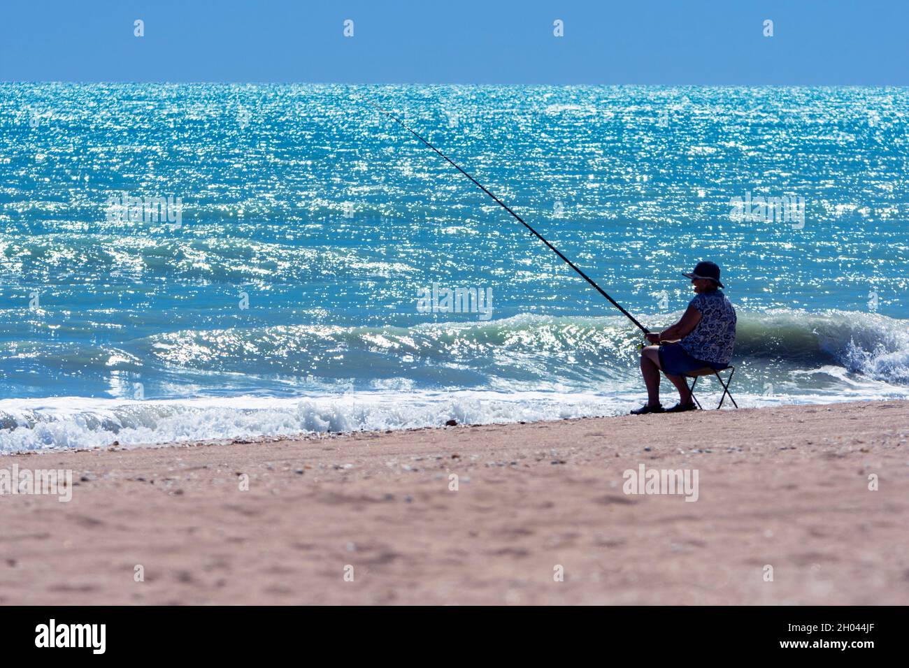 Lone fishermen sea fishing from a chair on the beach, Eighty Mile Beach ...