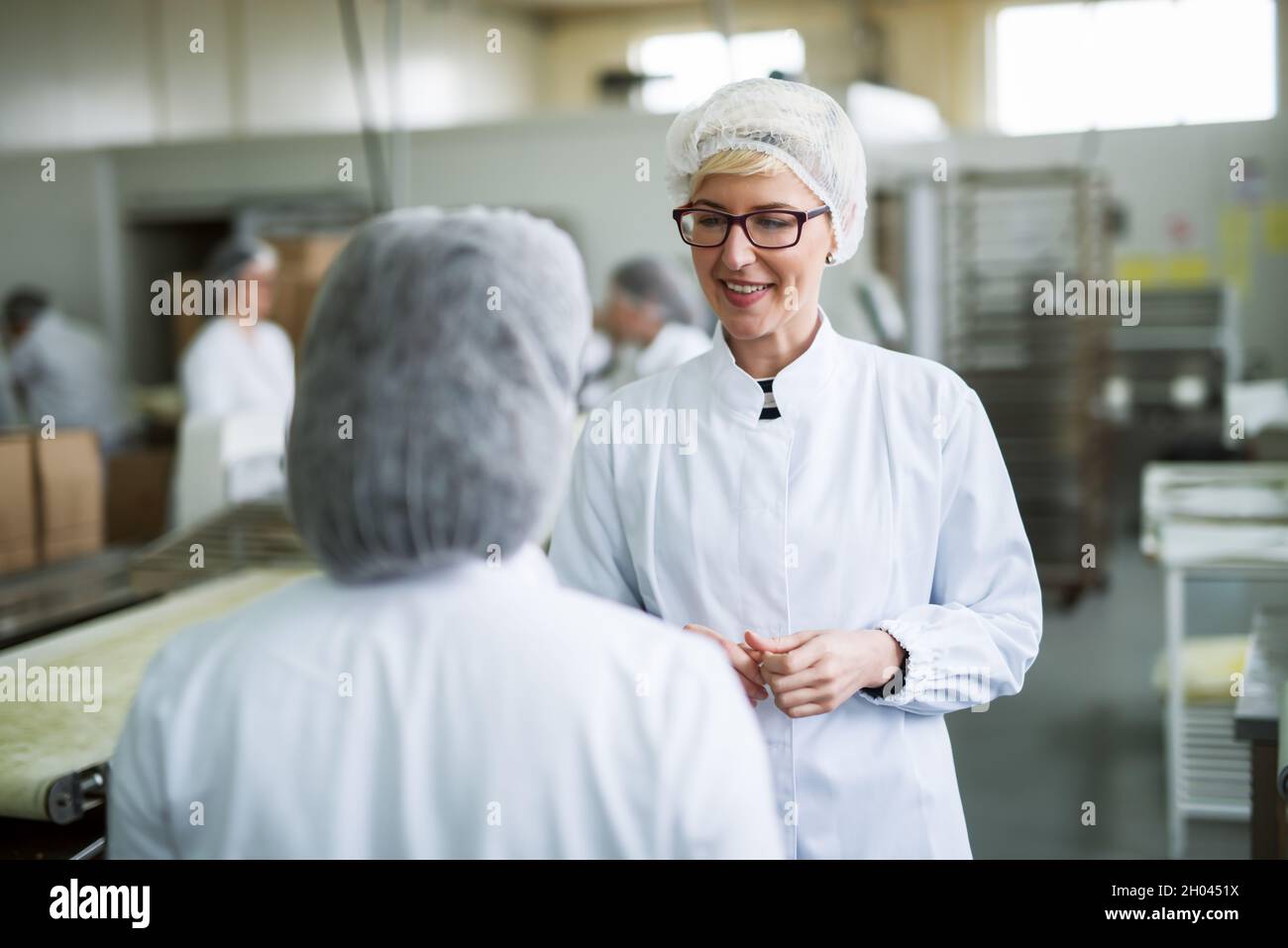 Two female workers discussing about food quality while standing in food ...