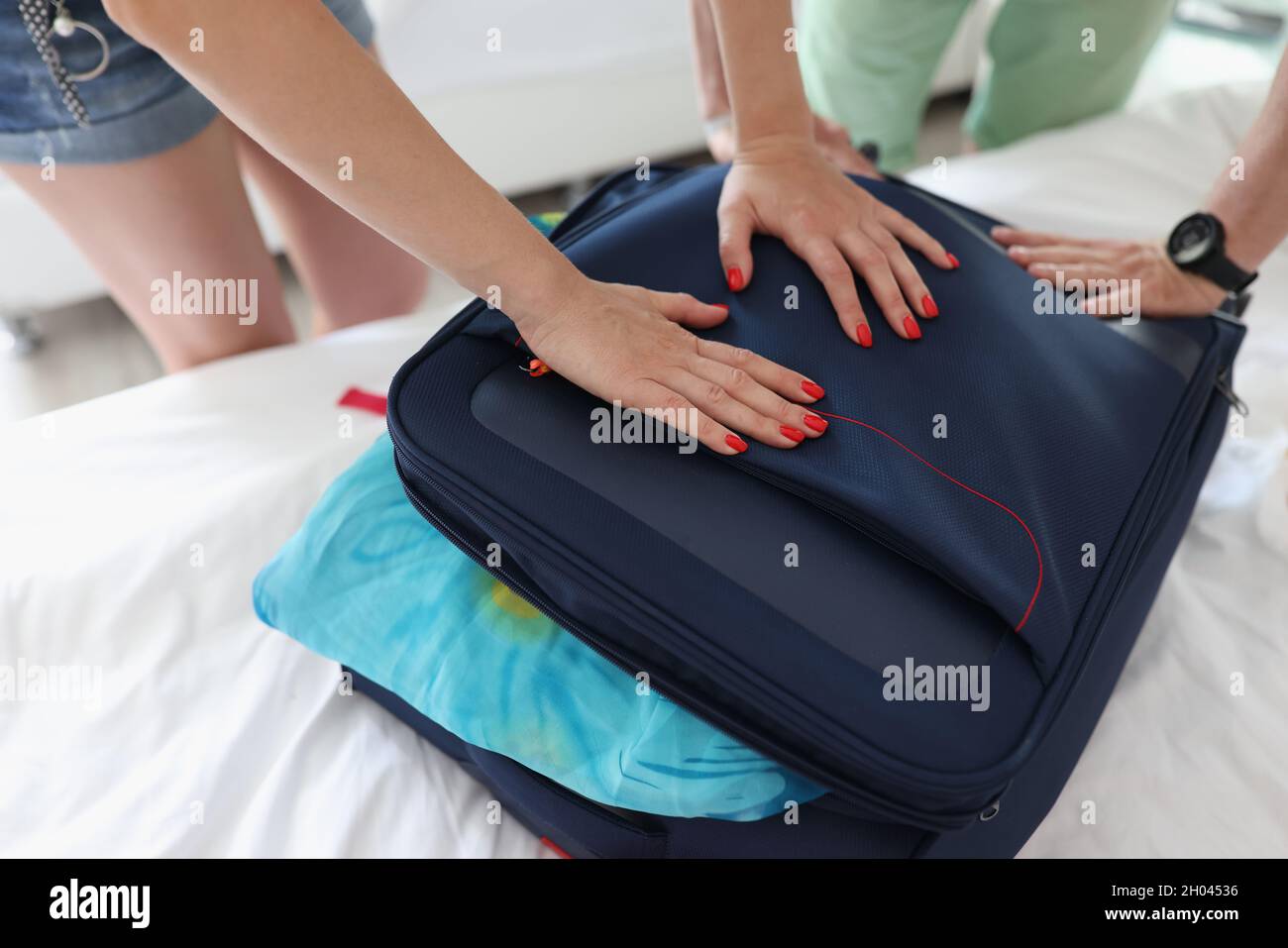 Man and woman trying to close full suitcase with things closeup Stock ...