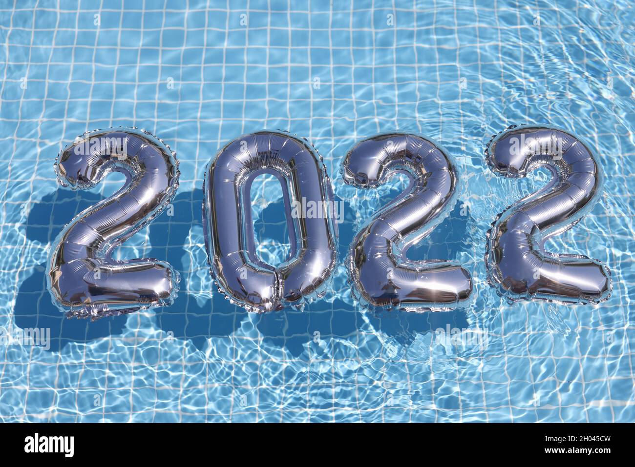 Silver helium balloons with numbers 2022 floating in swimming pool ...