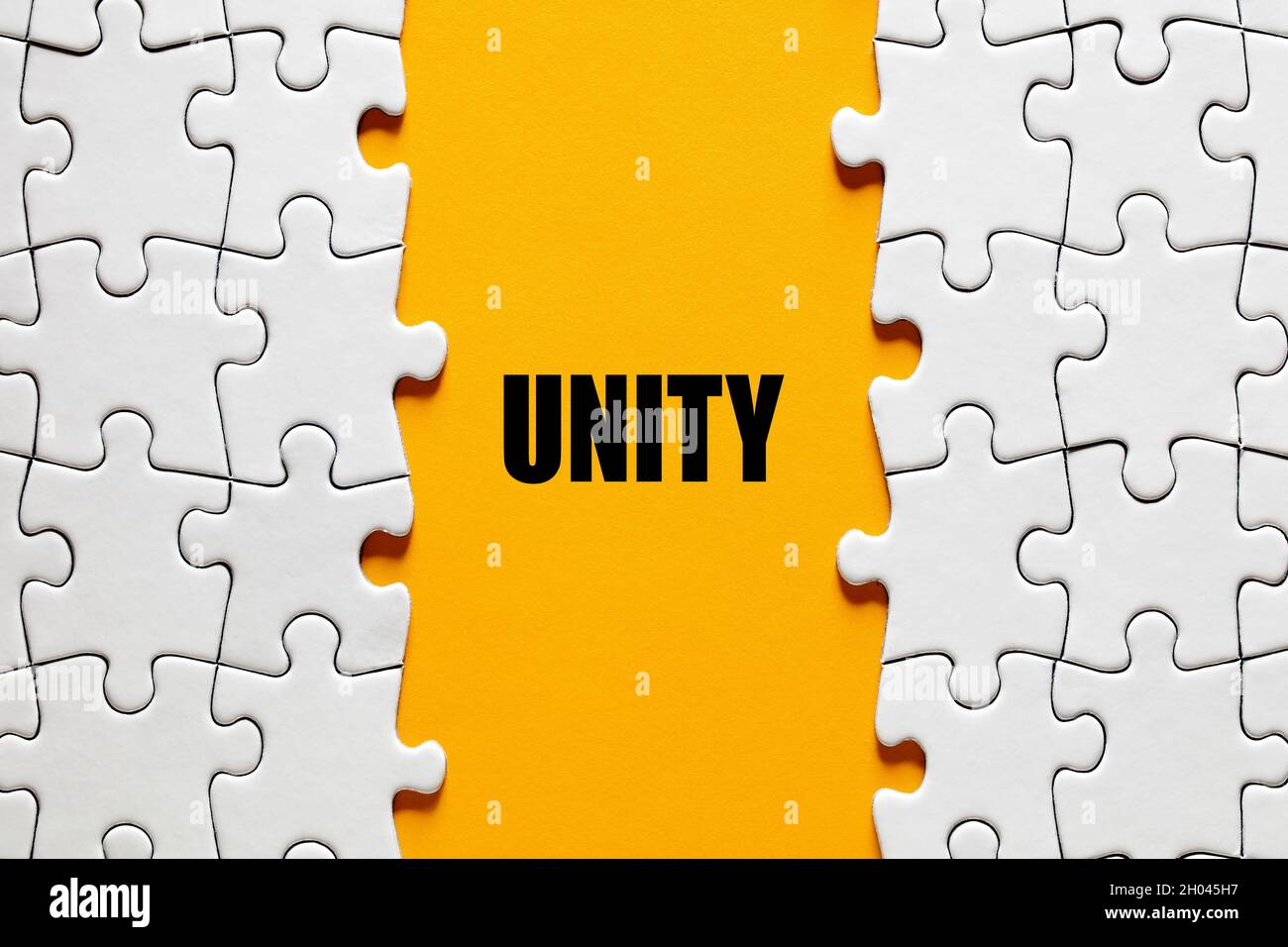 The word unity on yellow background between the jigsaw puzzle pieces ...