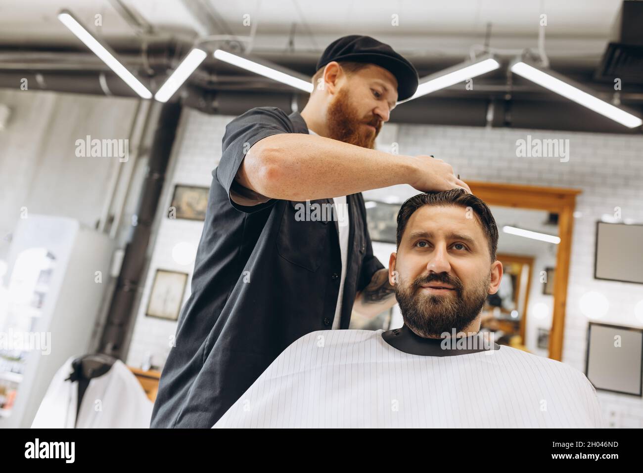 Two handsome men at barbershop. Stylish red-bearded barber and client ...