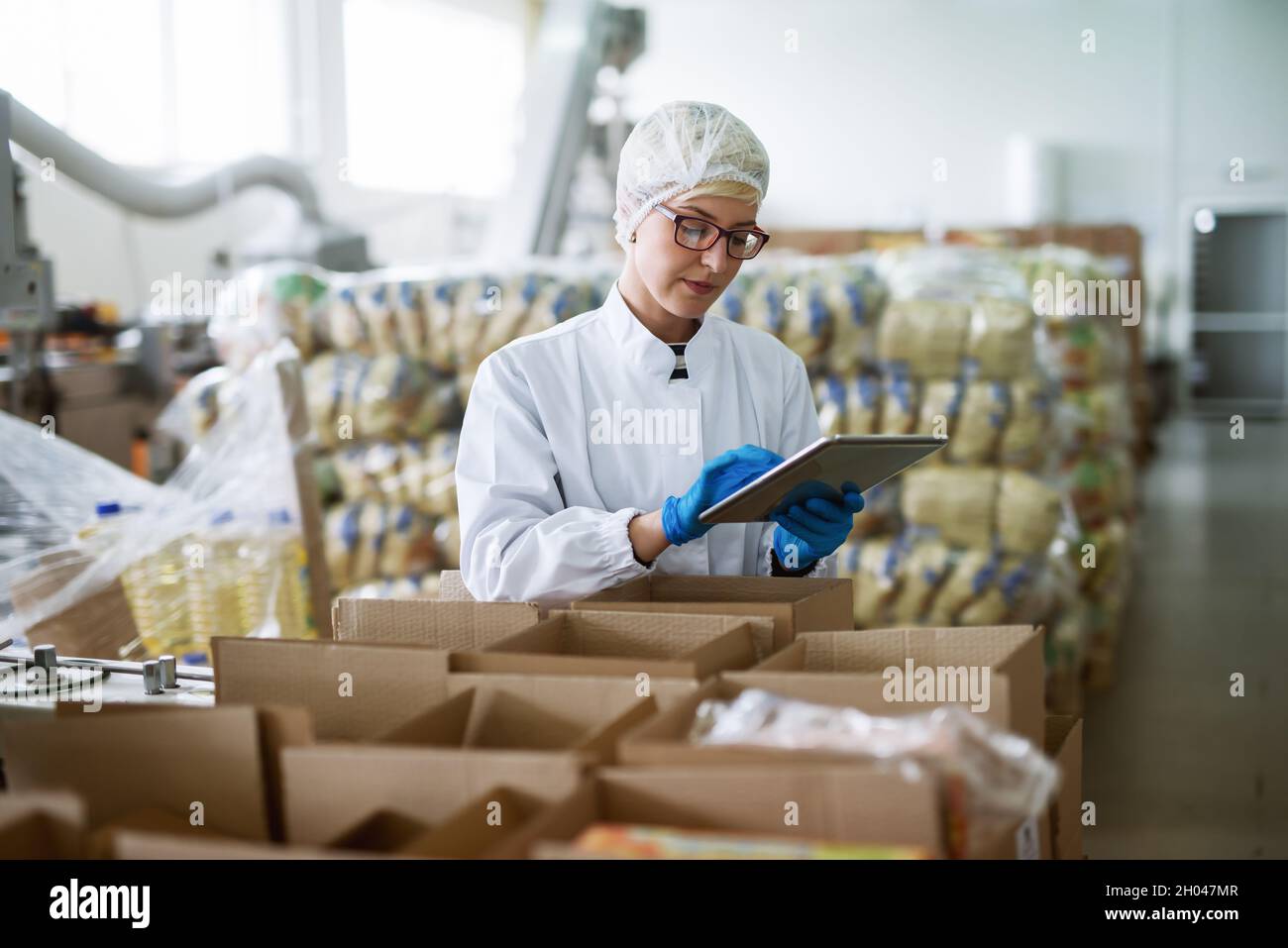 Female worker using tablet for checking boxes while standing in food factory Stock Photo - Alamy