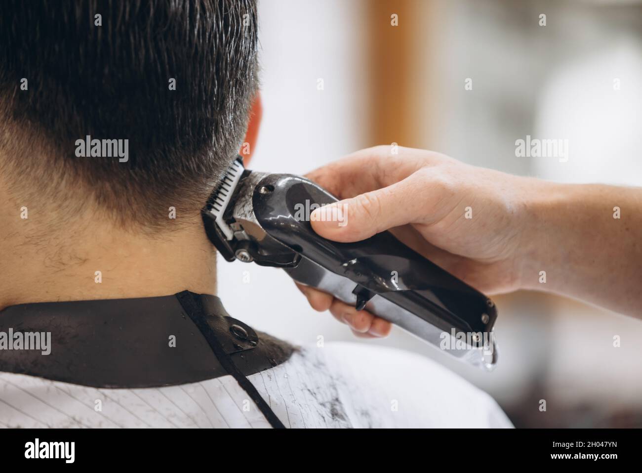 Close-up professional barber cuts the hair, beard of man at barbershop ...