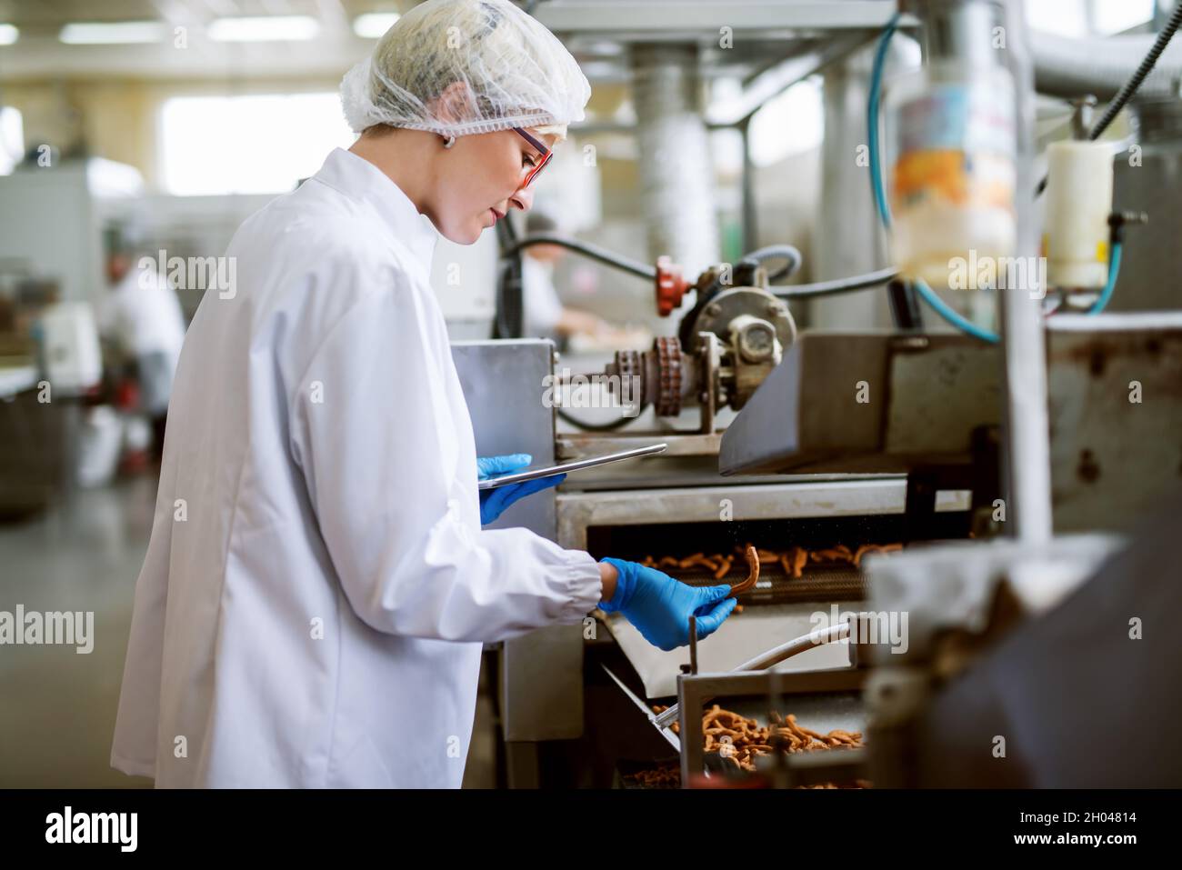 Female worker using tablet for controling products while standing in ...
