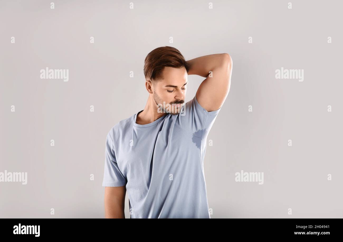 Sweaty man with stain on t-shirt against gray background. Using ...