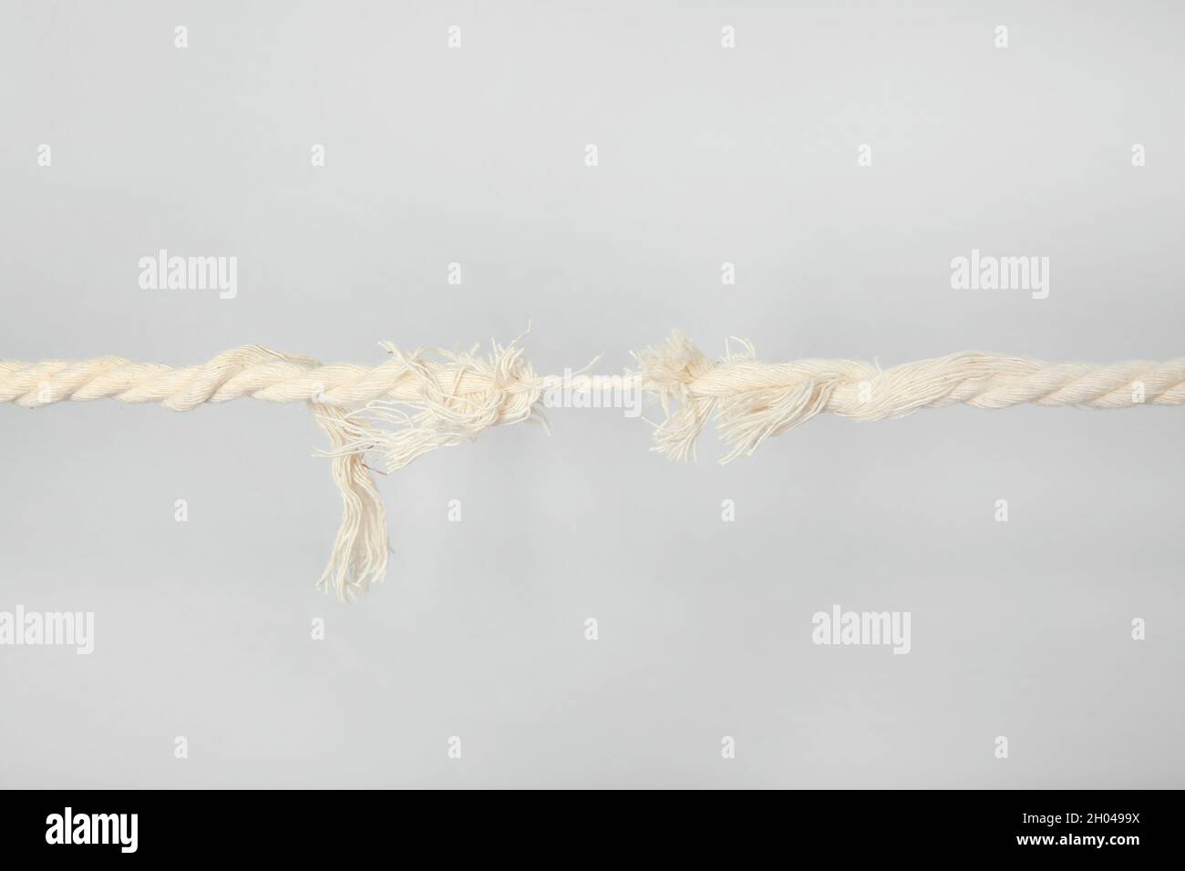 Frayed rope at breaking point on gray background Stock Photo - Alamy